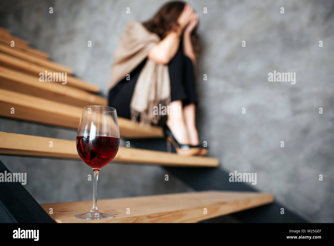 Young woman has problems with alcohol. Sitting on steps and hiding face ...