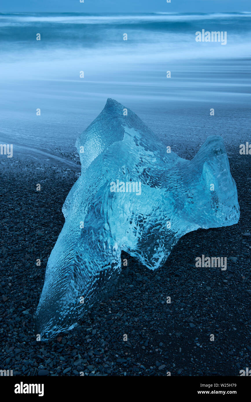 Stranded ice block on a lava beach. Jokulsarlon glacier bay, Iceland ...