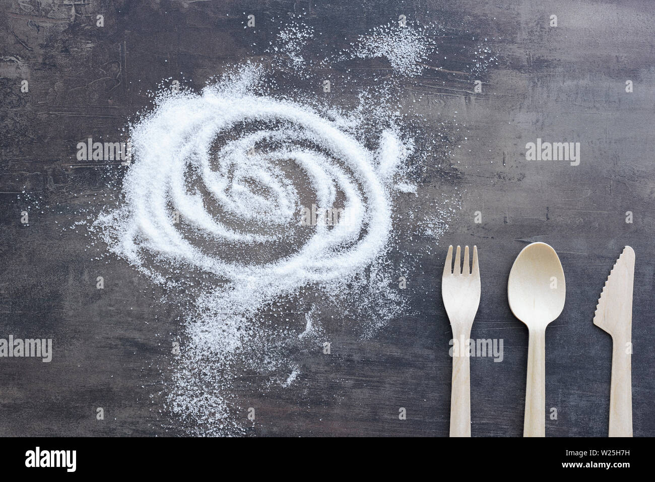 Top view of scattered sugar and fork, spoon, knife from wood. All on ...