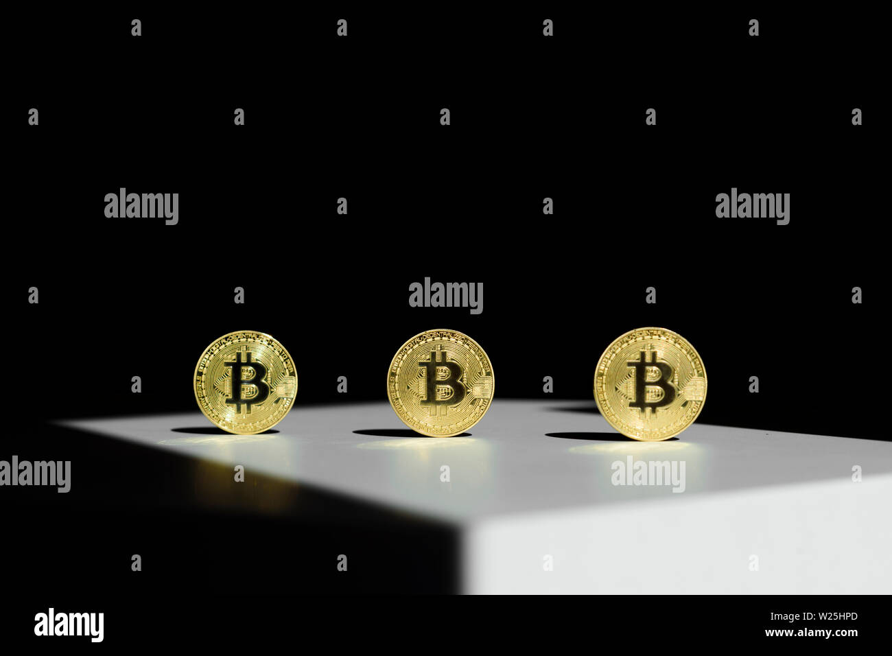 Three gold shiny coins with a bitcoin symbol in a sun ray with shadow ...