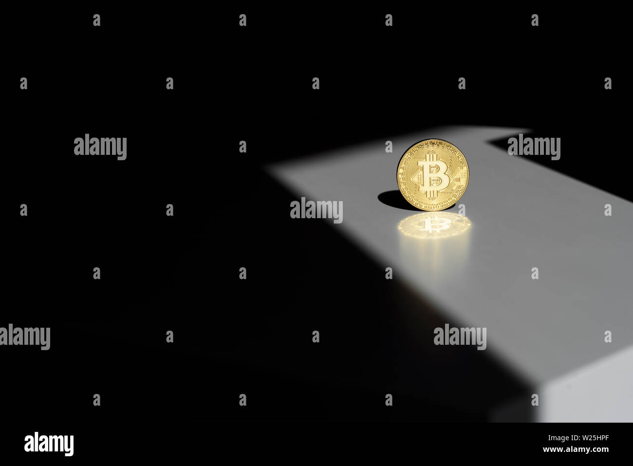 Gold shiny coin with a bitcoin symbol in a sun light with shadow around ...