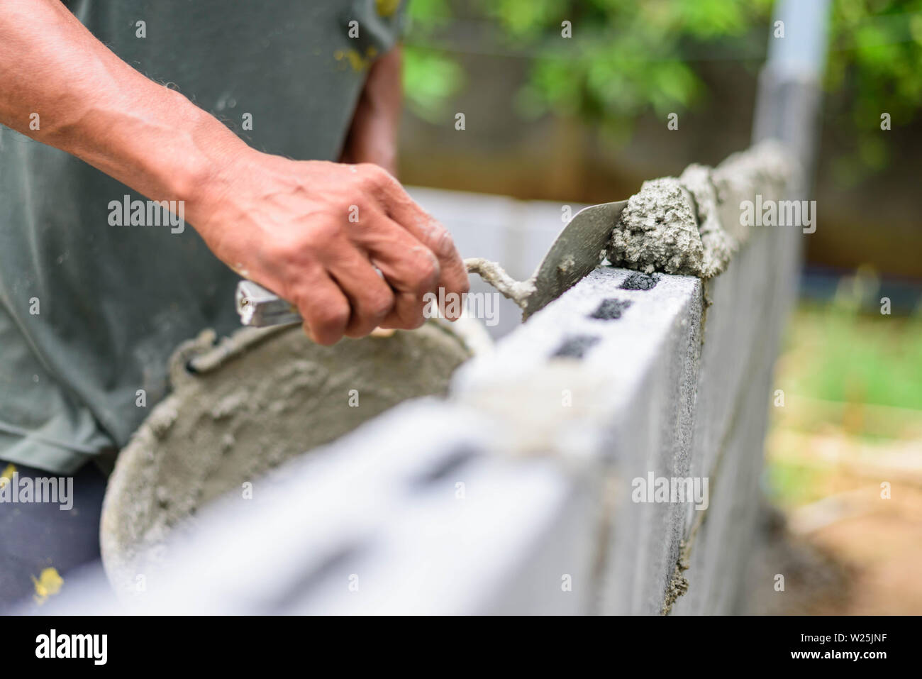 Worker brick the cement wall in construction site Stock Photo - Alamy