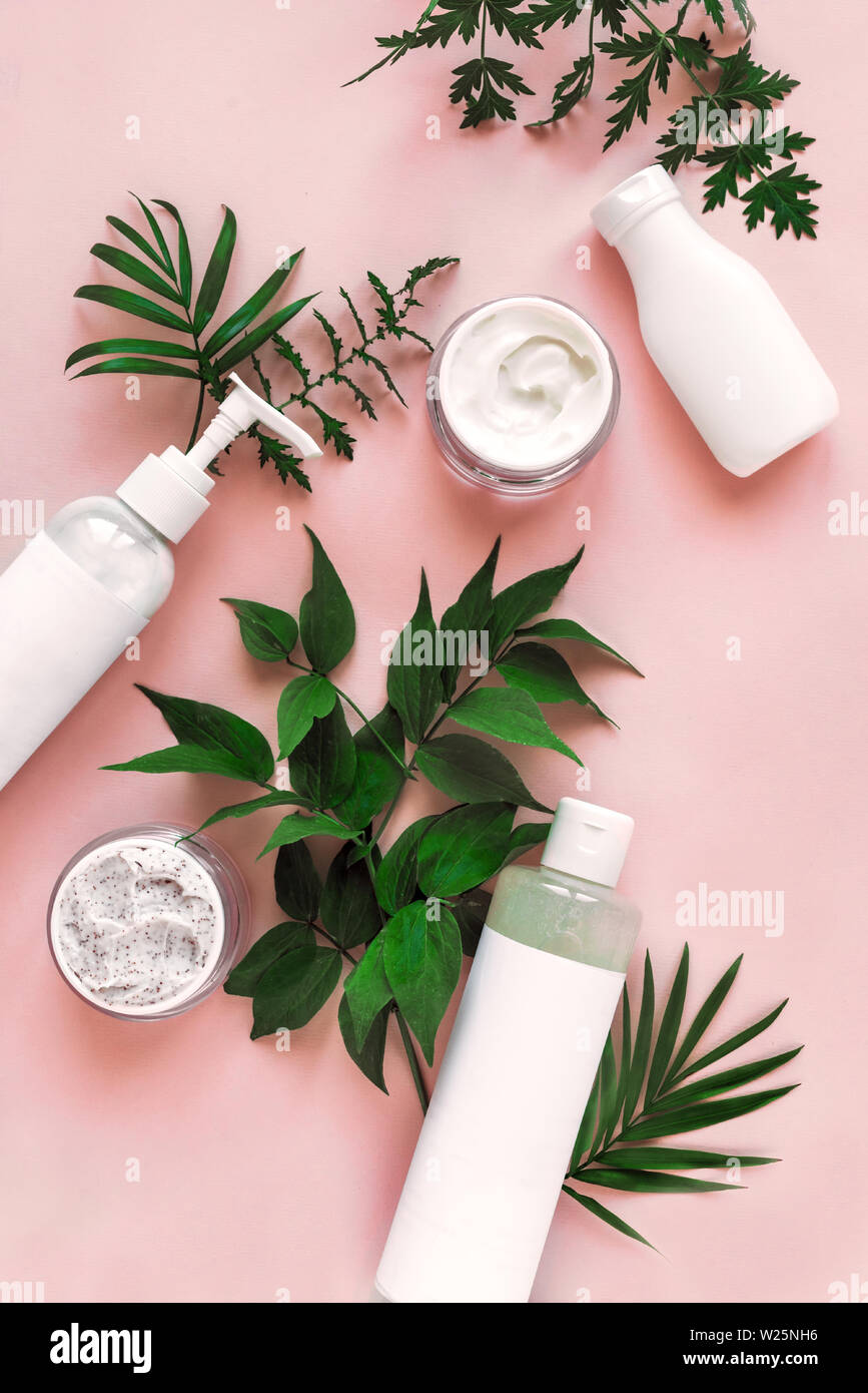 Natural cosmetics and green leaves on pink background, top view, flat ...
