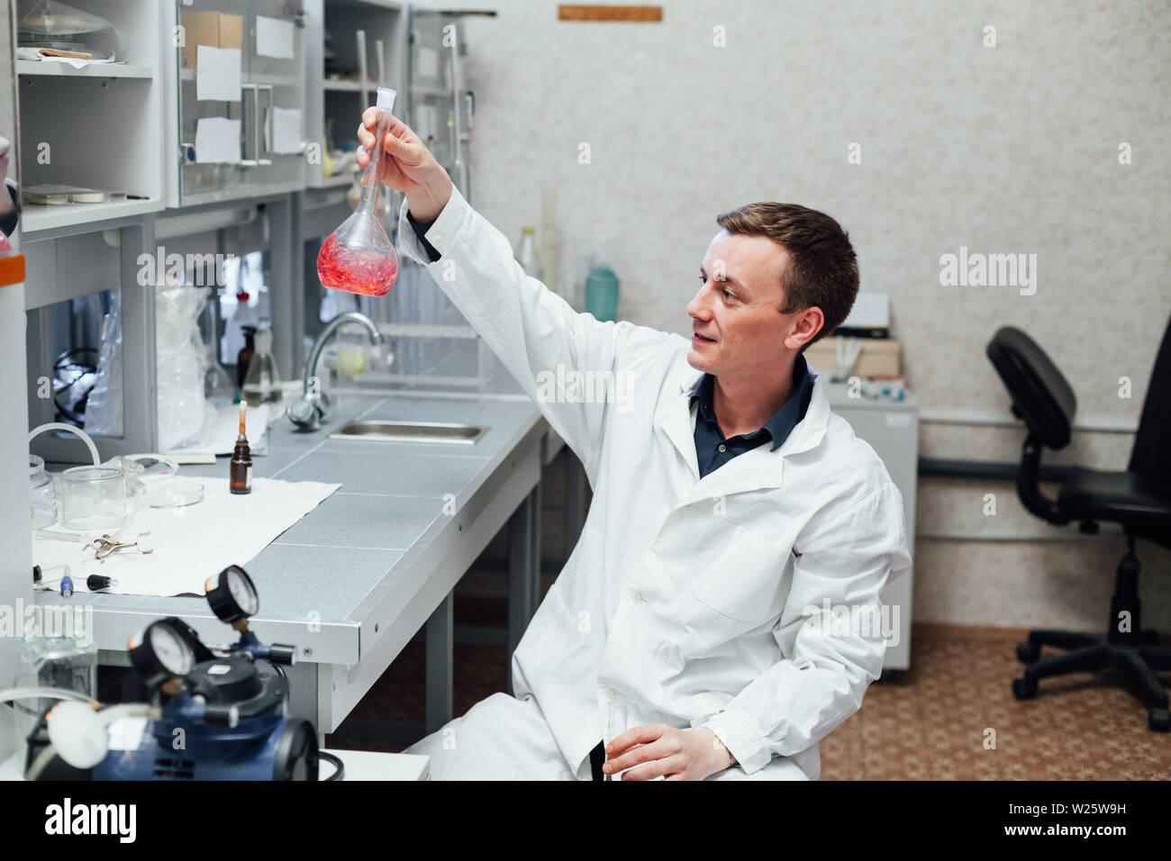 Investigator checking test tubes. Man wears protective goggles and mask ...
