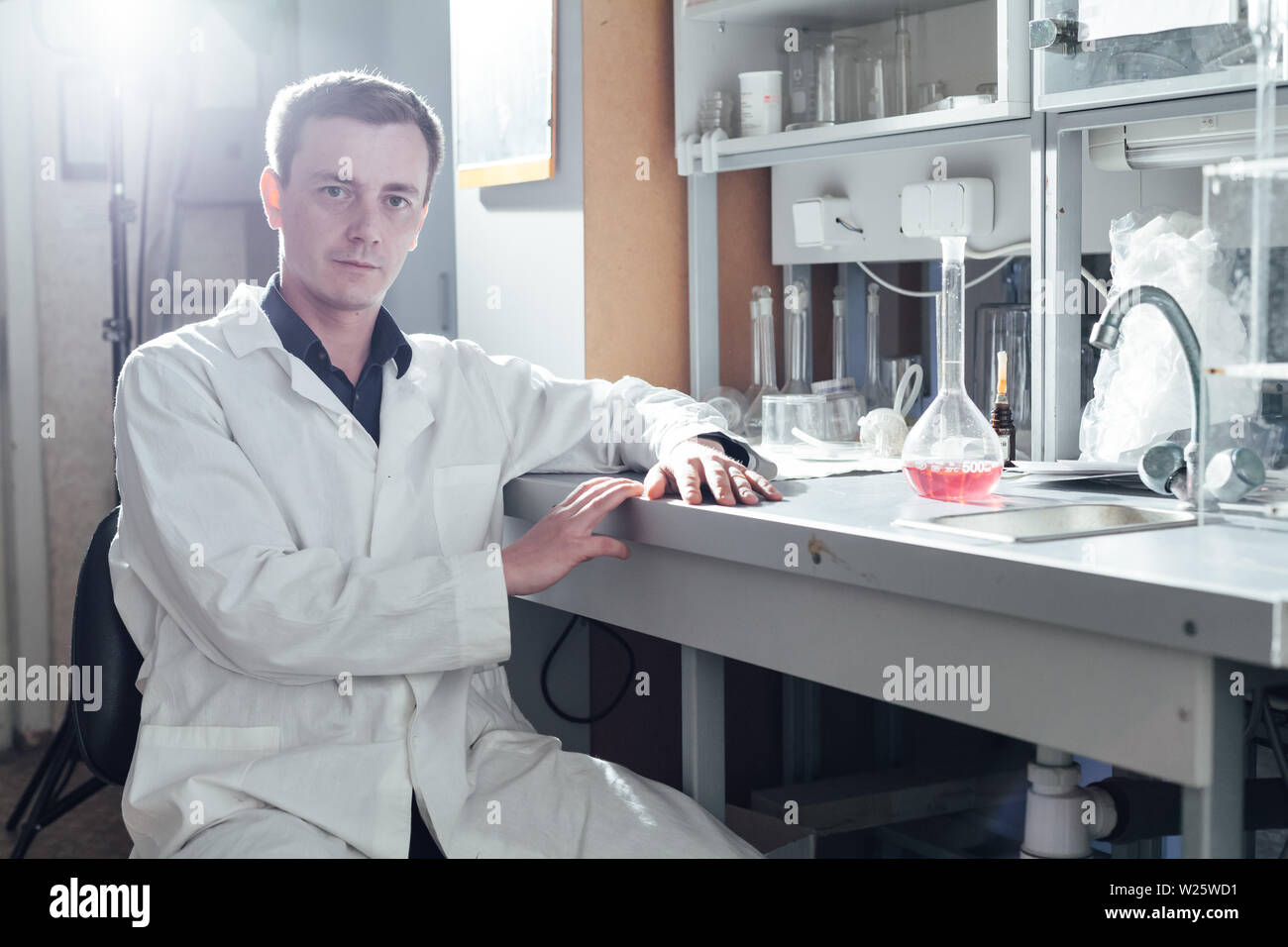 Investigator checking test tubes. Man wears protective goggles and mask ...