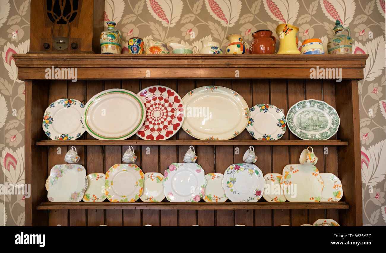 close up of an rusty wooden cupboard with old plates stored in a row ...