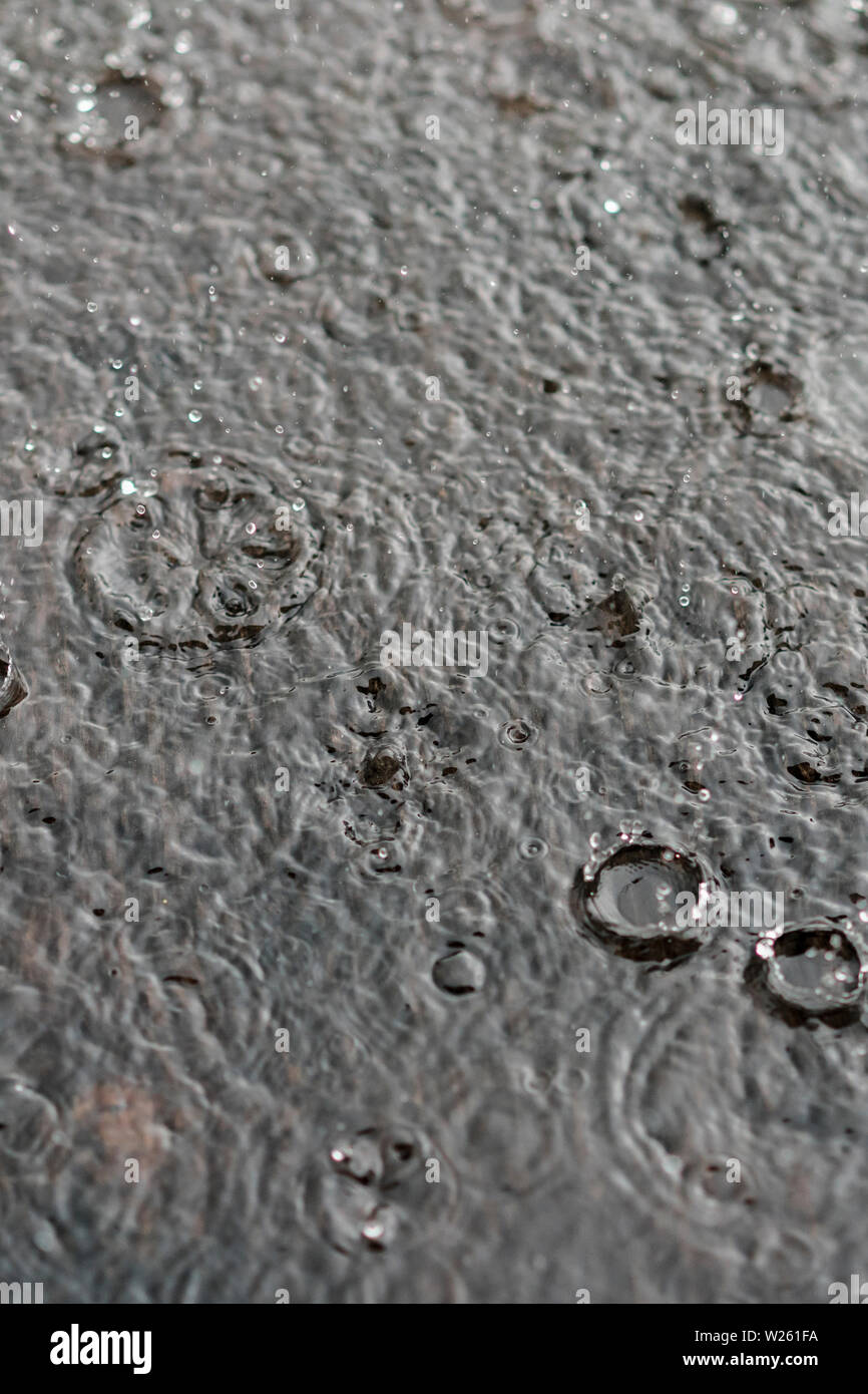rain gray background. Drops on a puddle. Vertical photo Stock Photo - Alamy