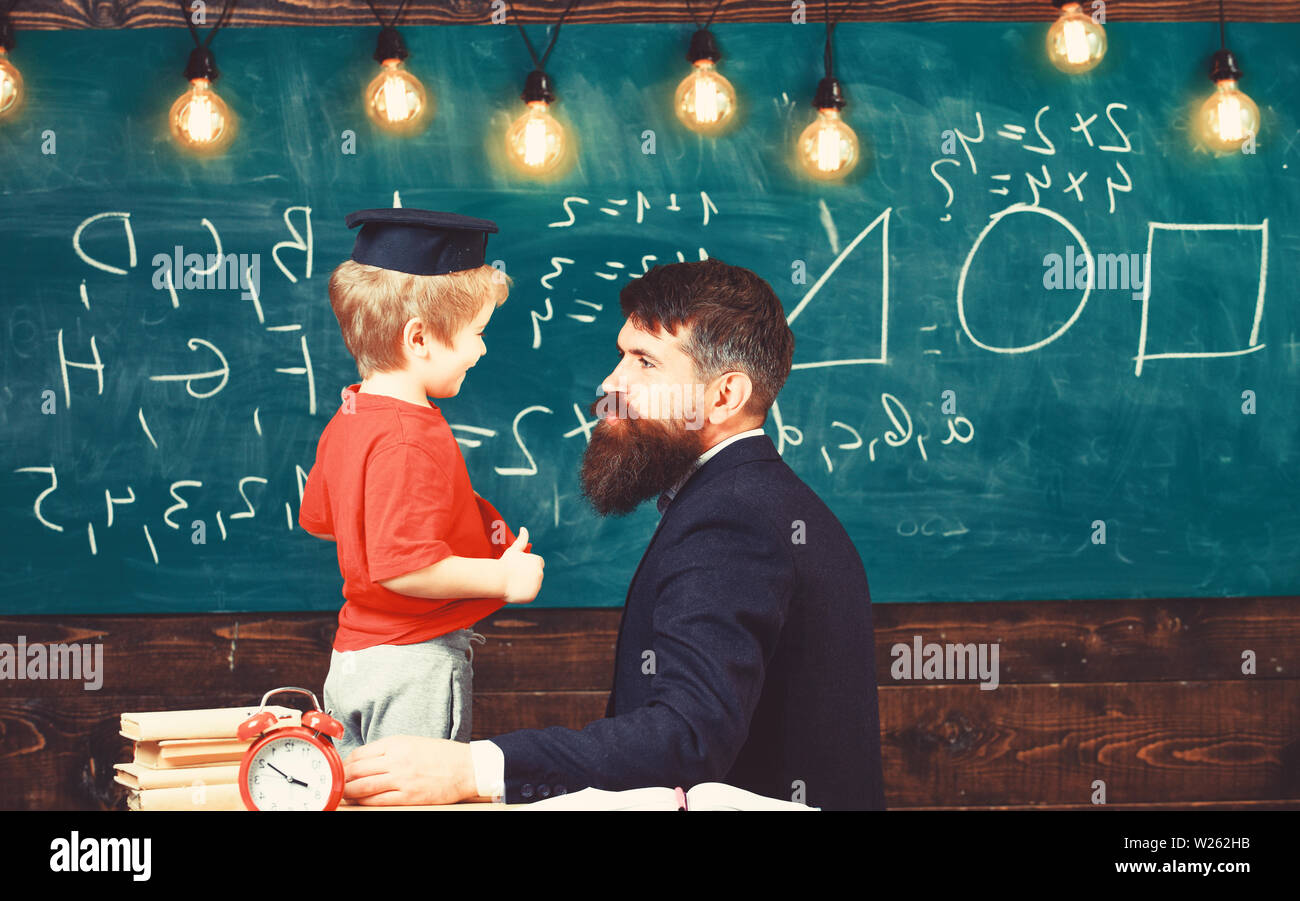 Teacher with beard, father teaches little son in classroom, chalkboard ...