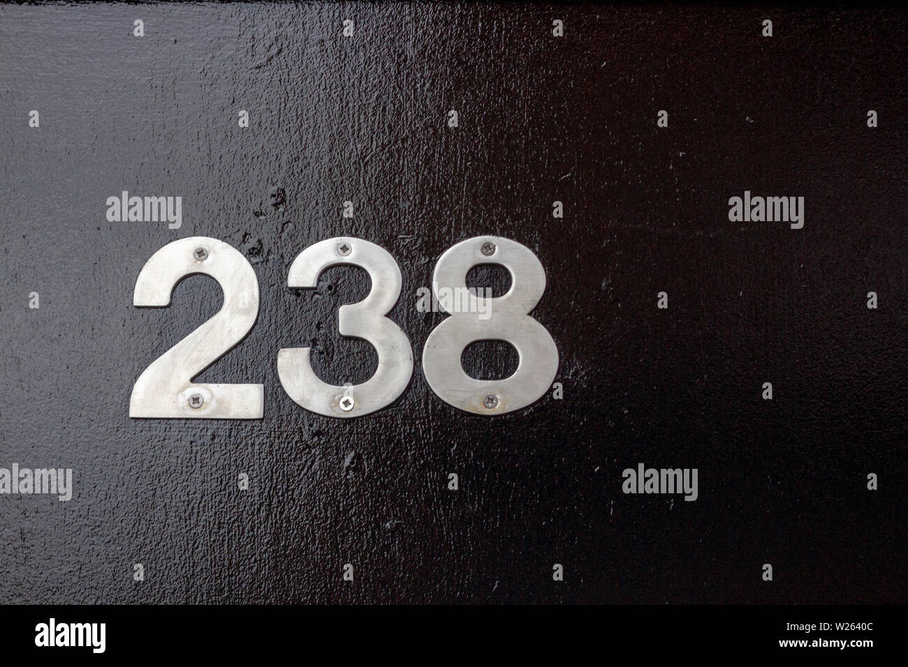 House number 238 with the 238 in metal digits on a wooden front door ...