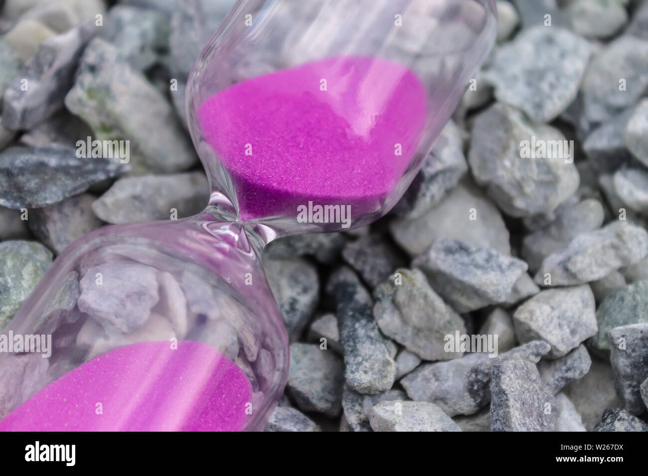 Hourglass with pink sand on small stones, symbol of time Stock Photo ...