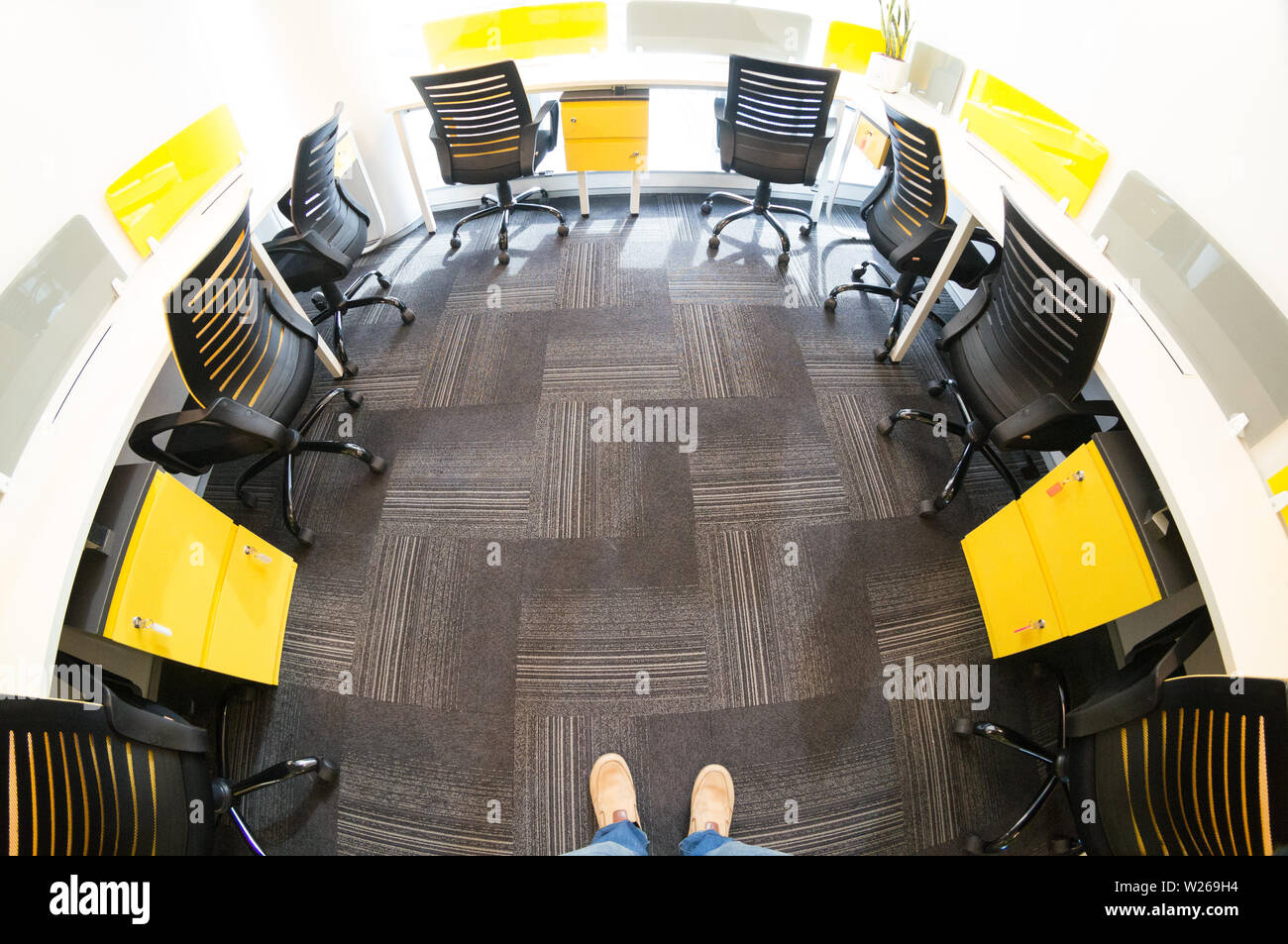 Fisheye shot of office with grey carpet and yellow and black chairs ...