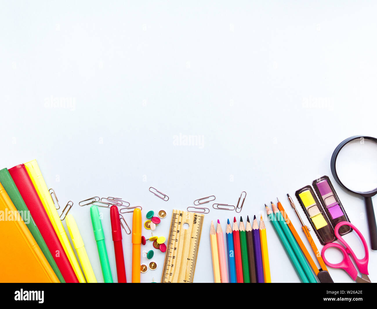 Colorful school suplies against light blue background with copy space ...