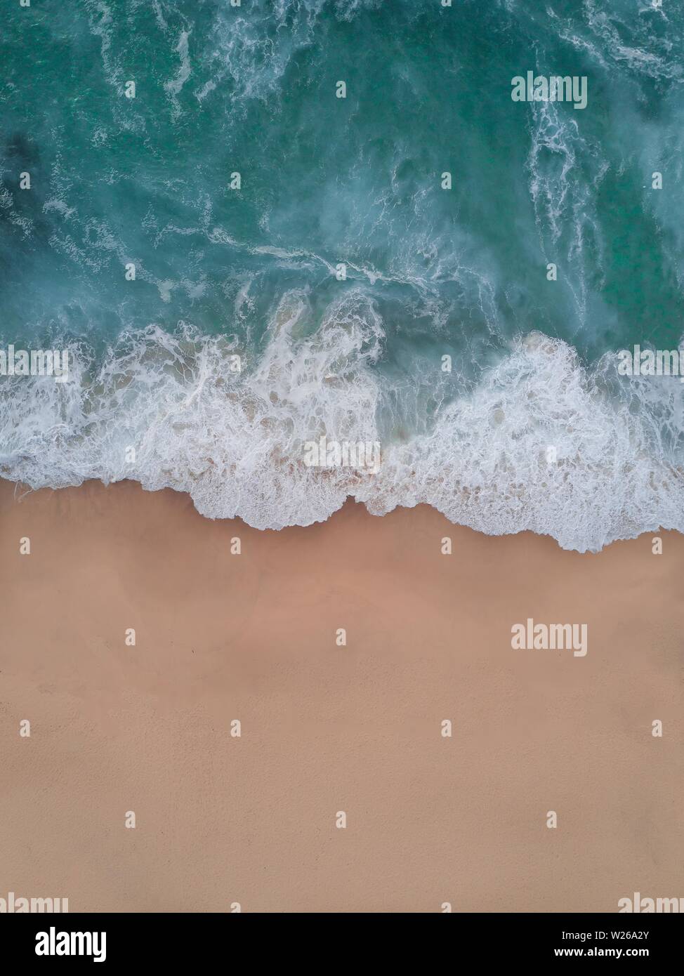 Aerial shot of beautiful splashing tall waves coming over the sandy ...