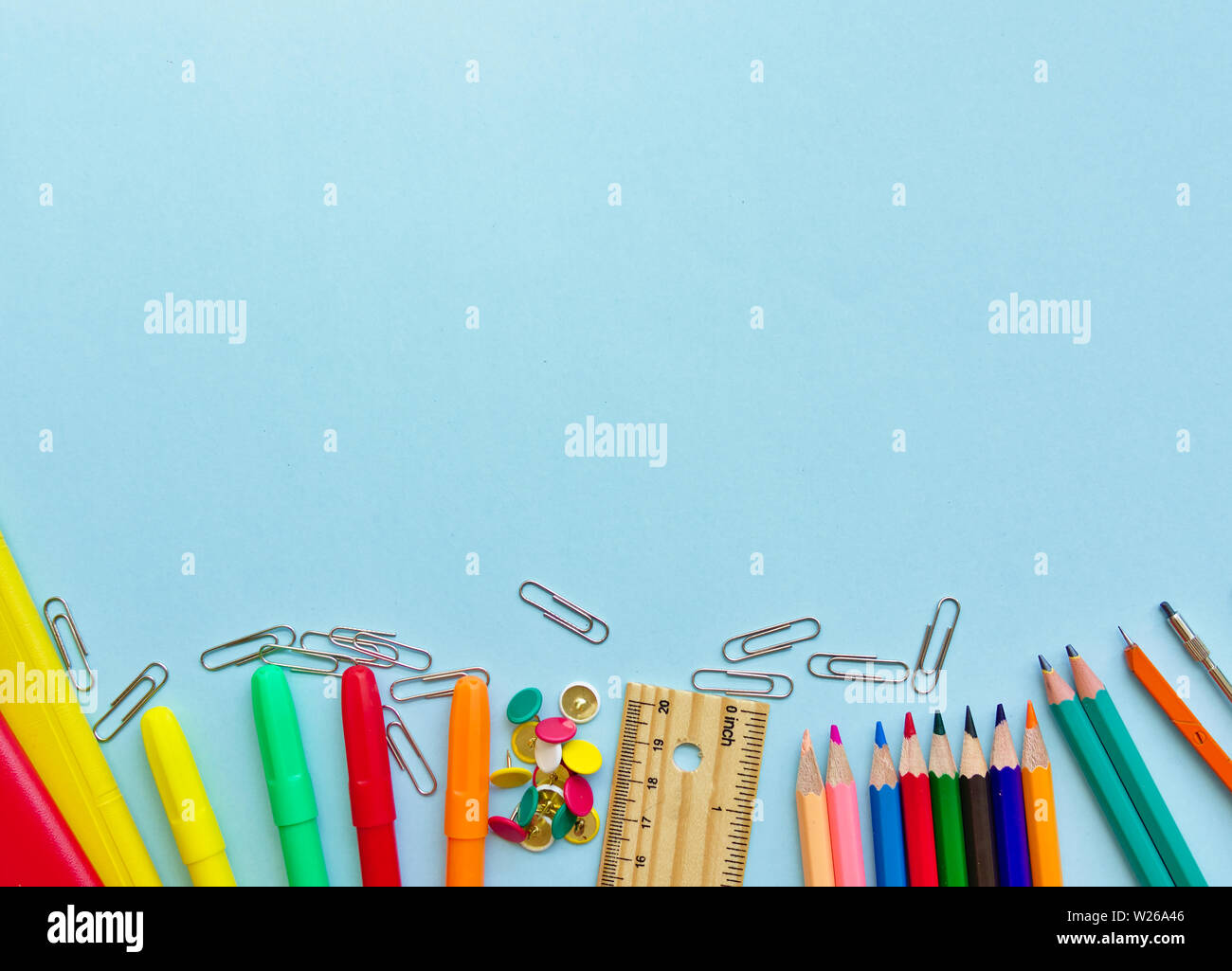 Colorful school suplies against light blue background with copy space ...