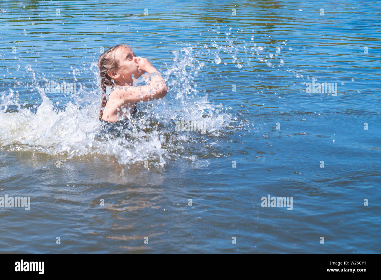little girl running through the water with a splash . in her hands ...