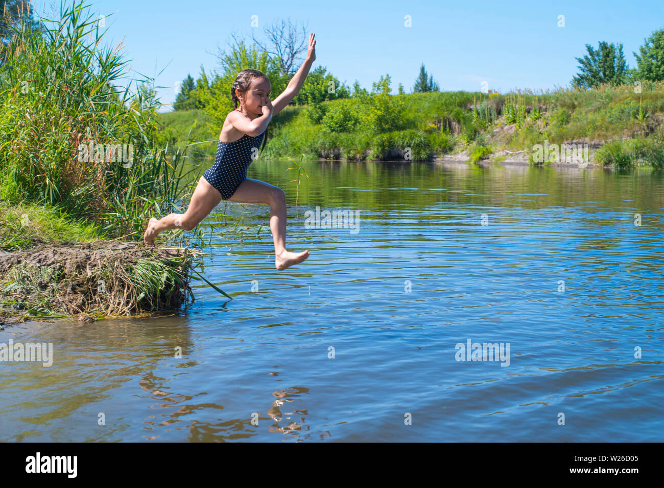 little girl running through the water with a splash . in her hands ...