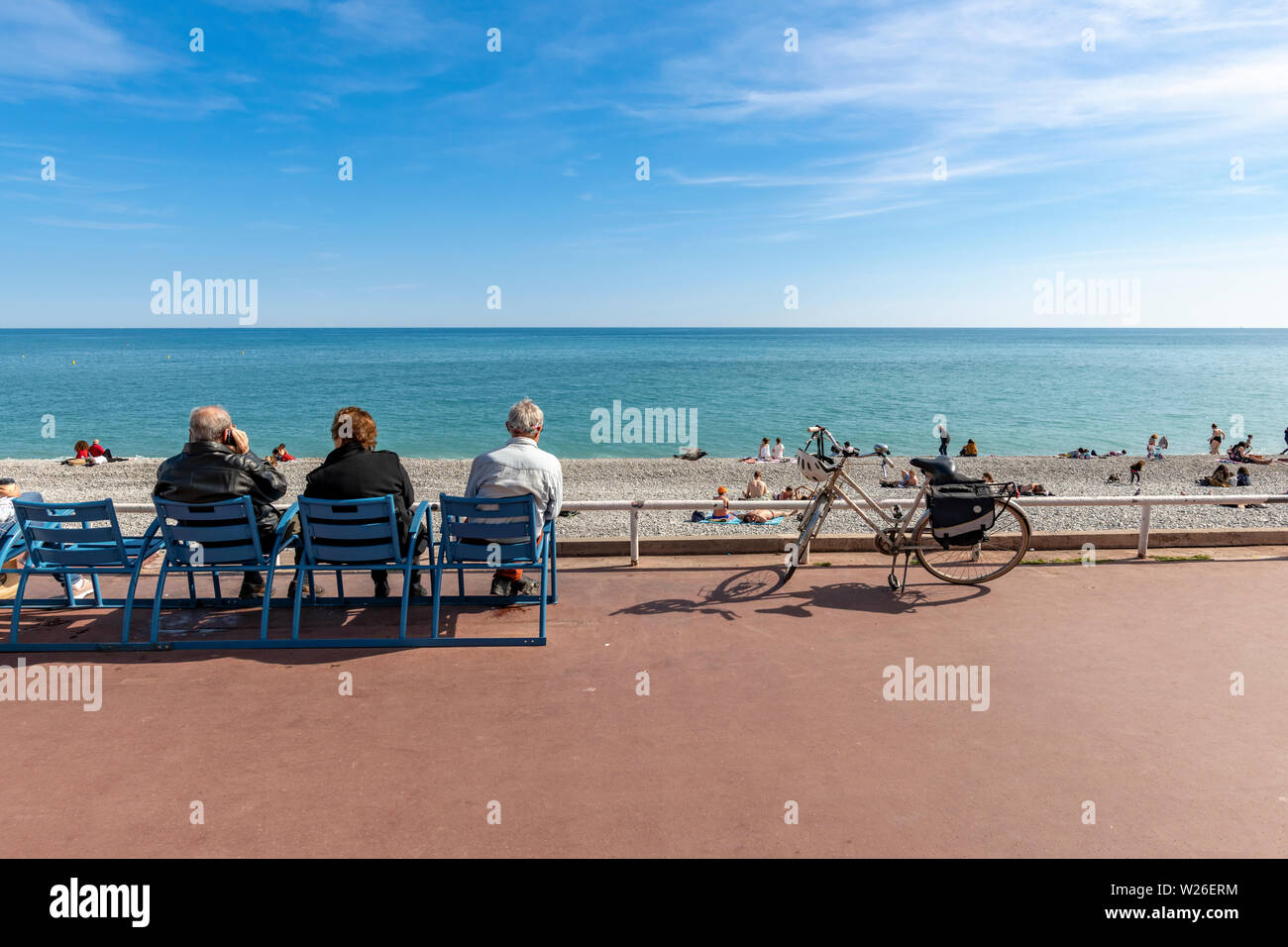 People sitting on a public bench and looking at the Mediterranean sea ...
