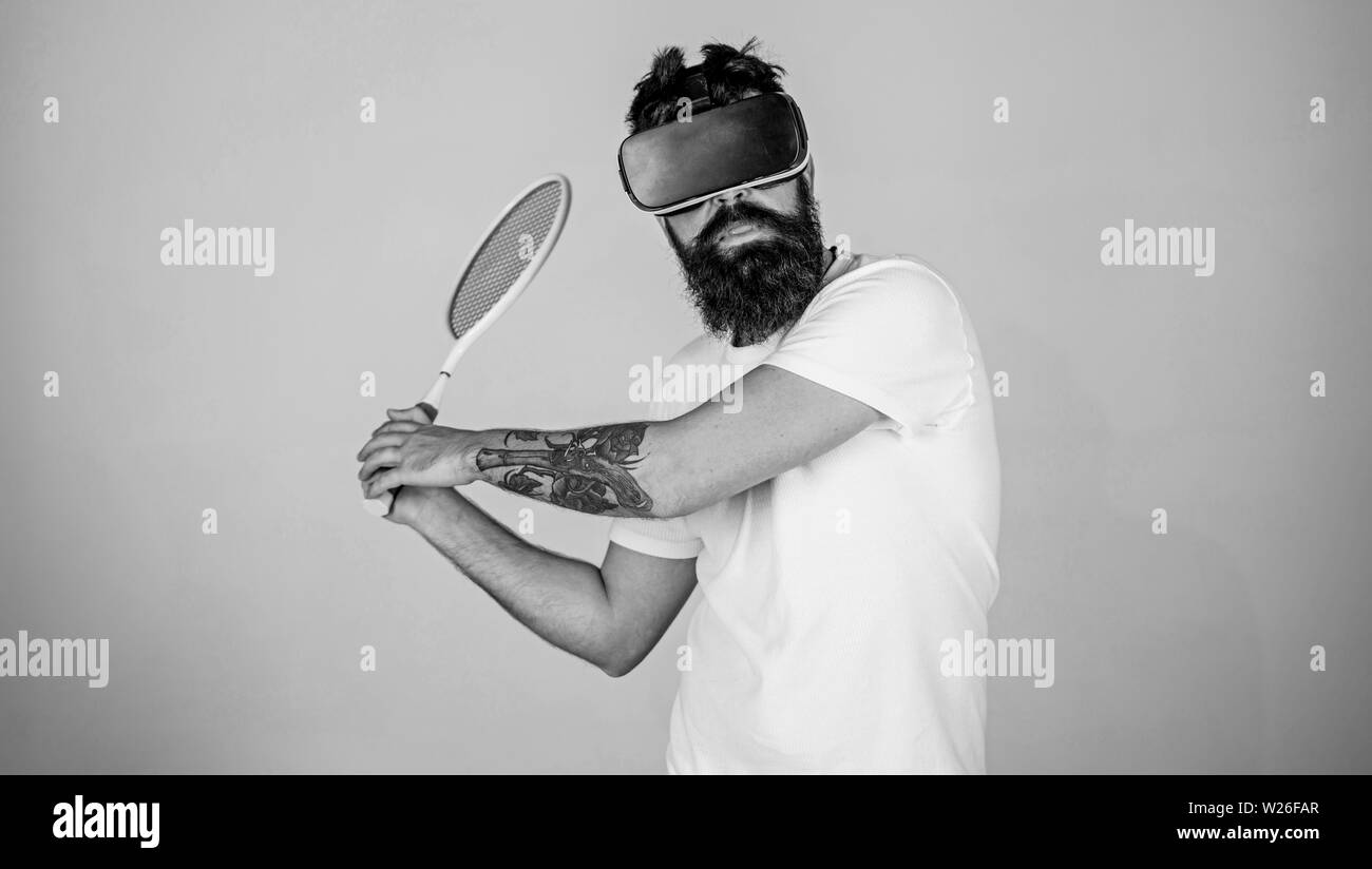 Guy with VR glasses play tennis with racket and ball. Man with beard in ...