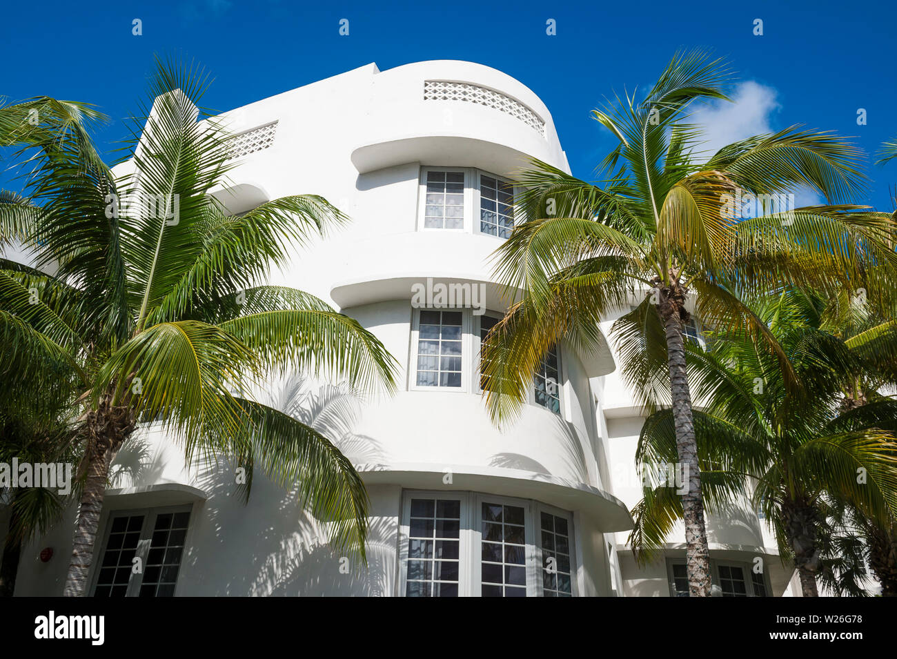 Classic curved 1930s Art Deco architecture and palm trees against blue ...