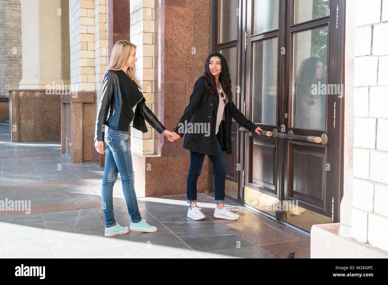 two students holding hands enter the university building Stock Photo ...