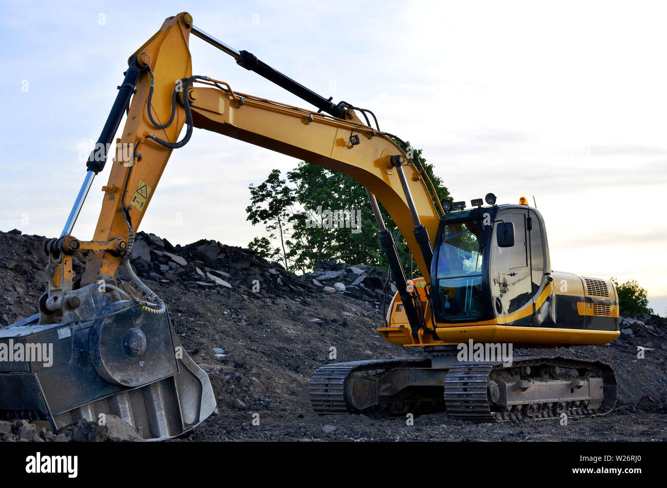 A heavy excavator in a working at granite quarry unloads old concrete ...