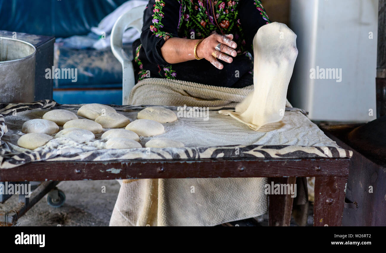 Close up Arabian old woman hand cooking flatbread or laffa or pita ...