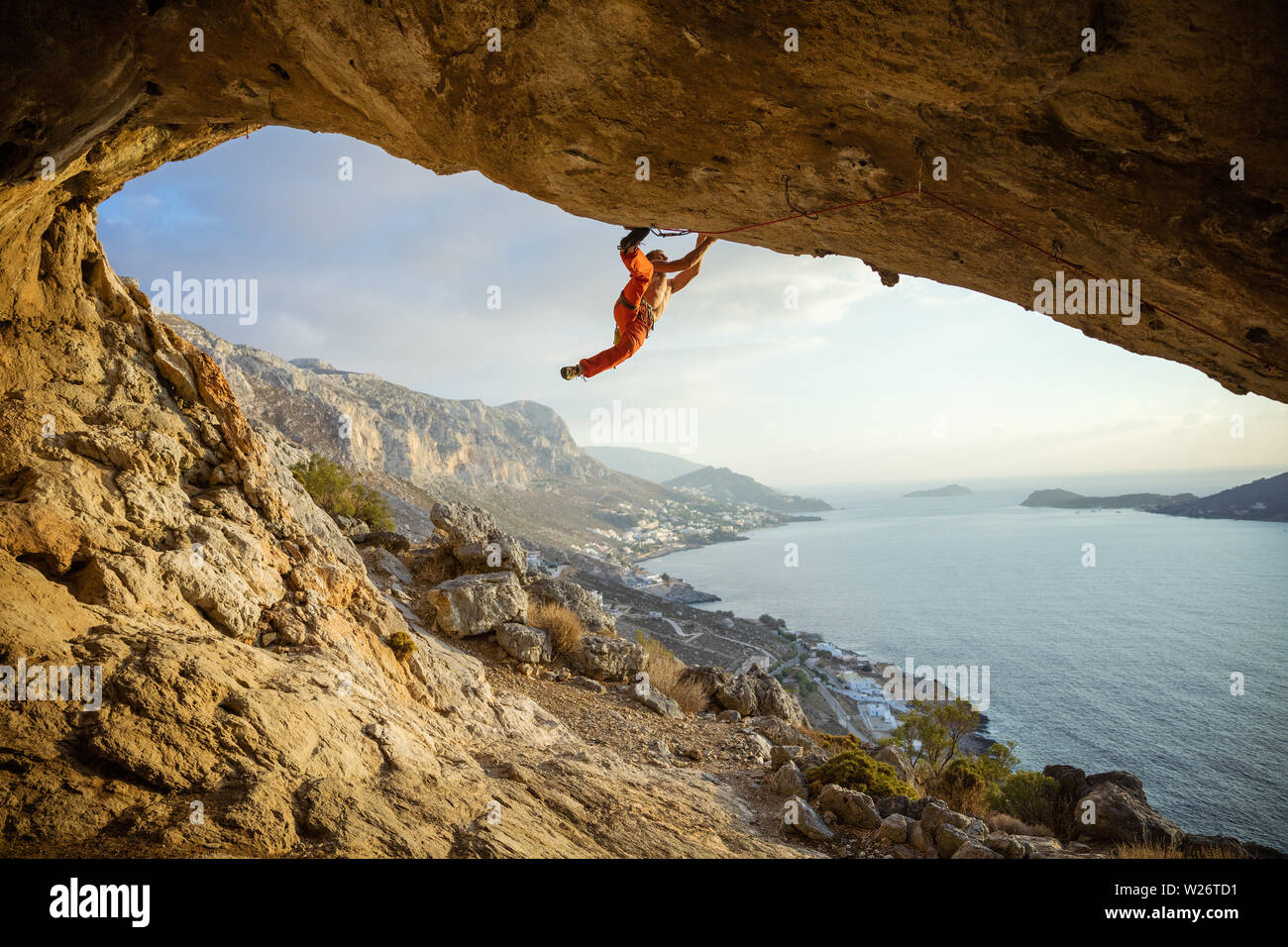 Young man climbing challenging route in cave against beautiful view of ...