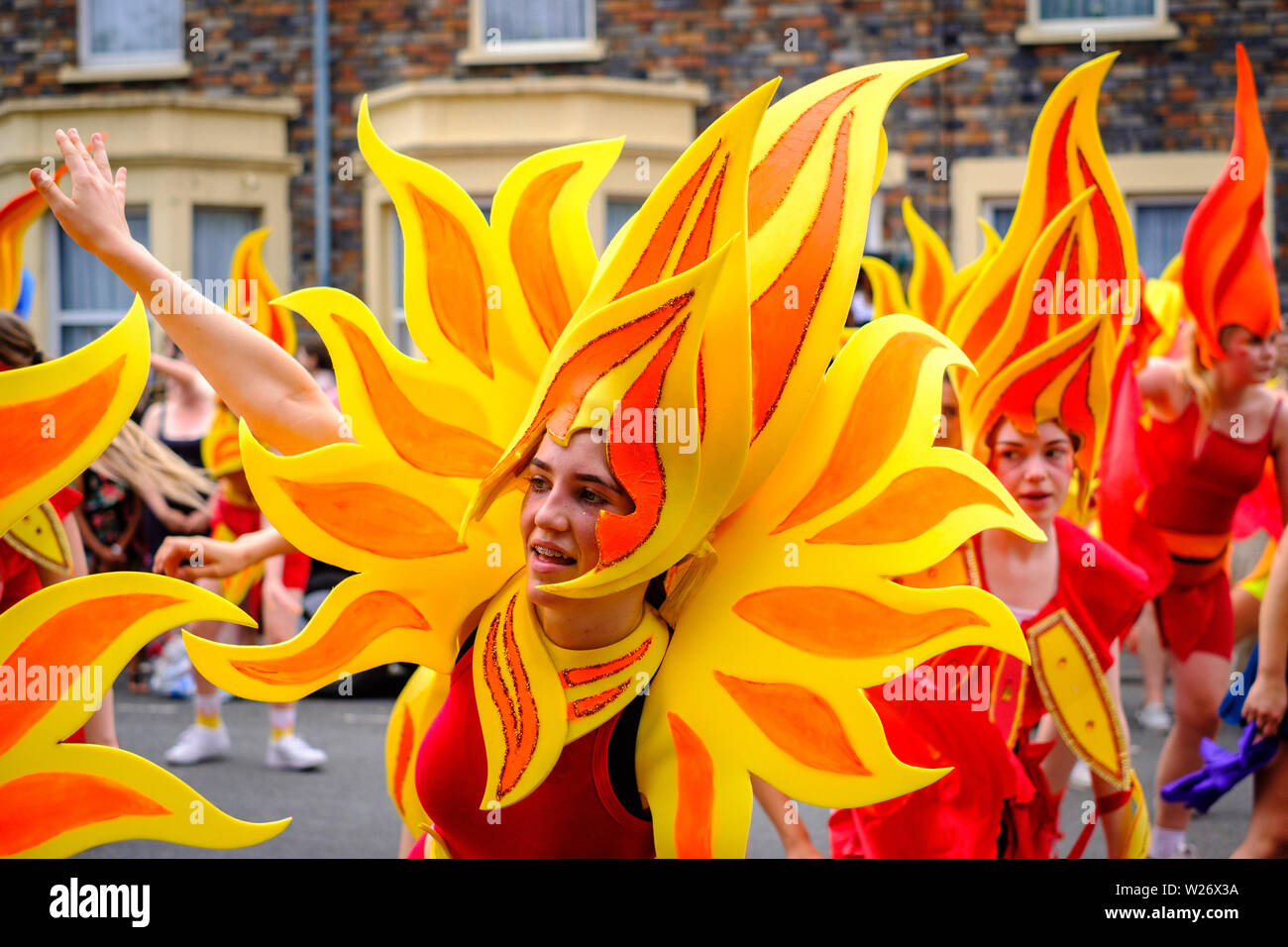 Female dancers wearing brightly coloured flame costumes in the parade ...