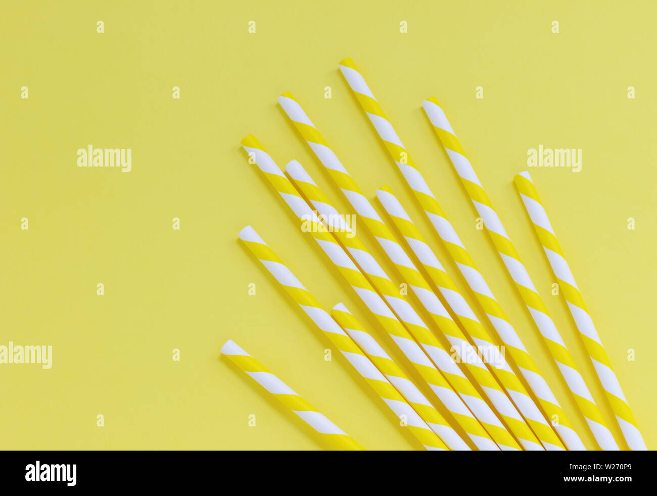 Yellow striped paper straws on a yellow background. Flat lay with copy ...