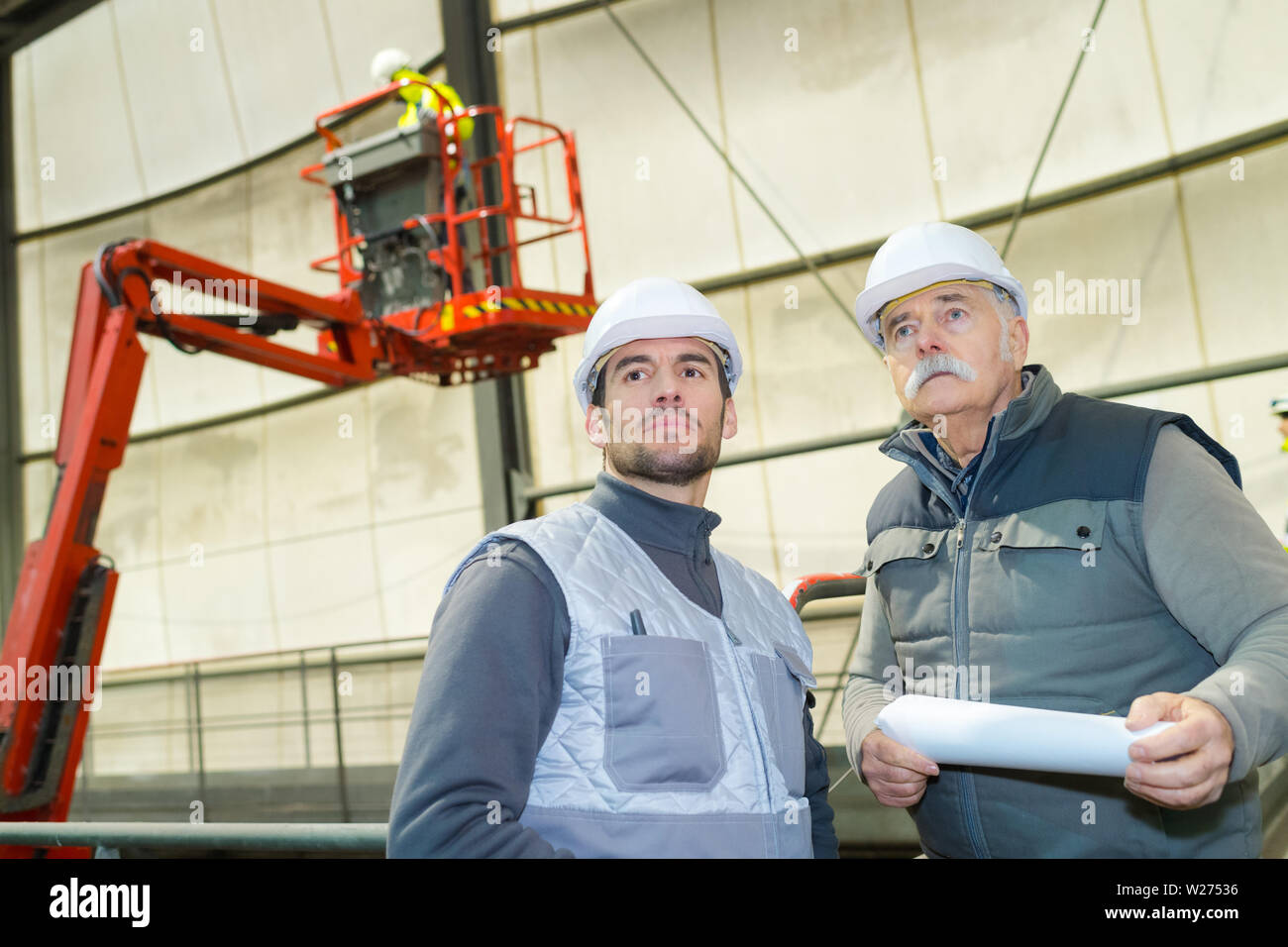 two male workers with cherry picker in background Stock Photo - Alamy