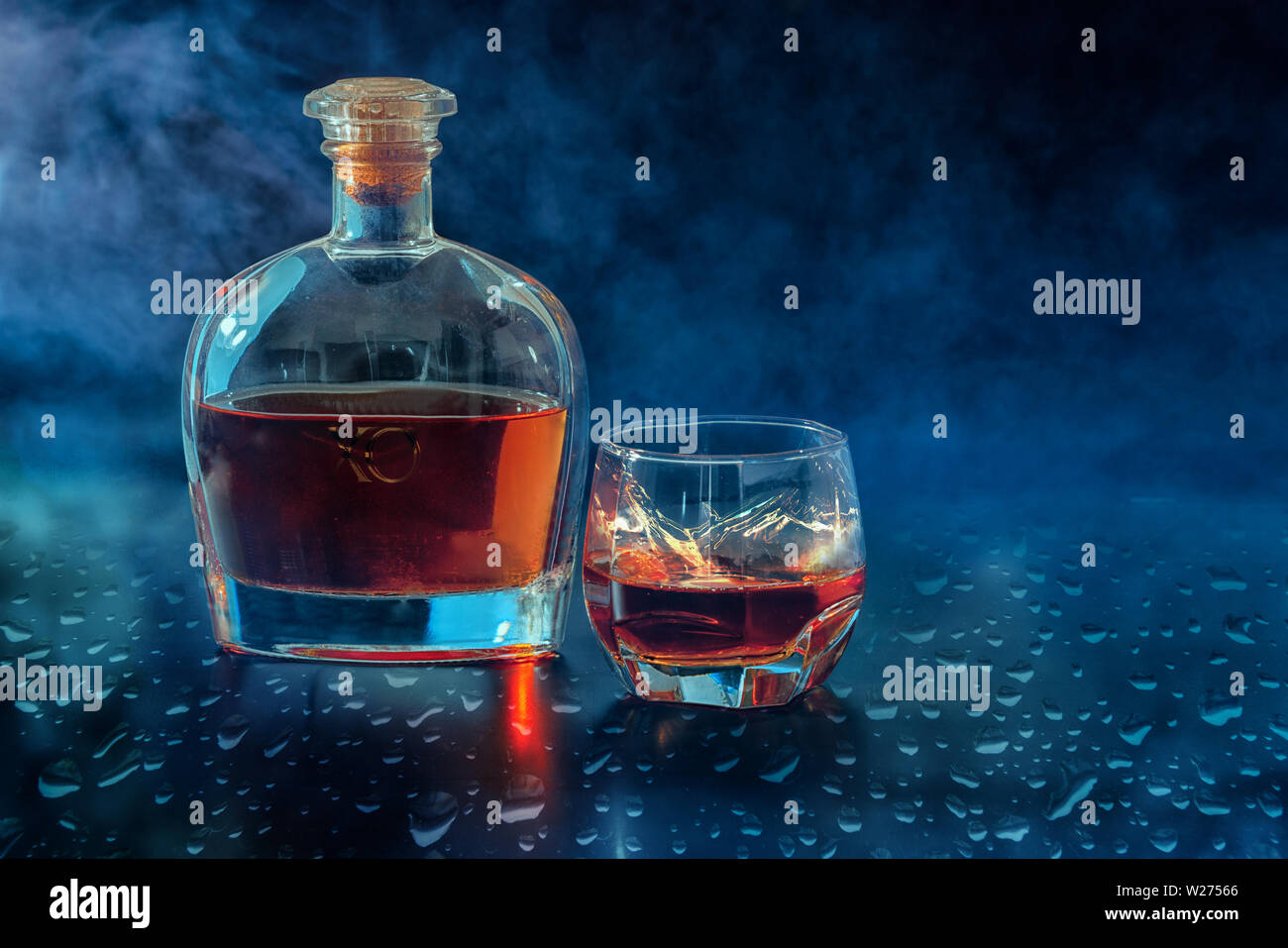 Bottle and glass of matured whiskey on a texture dark blue counter and ...