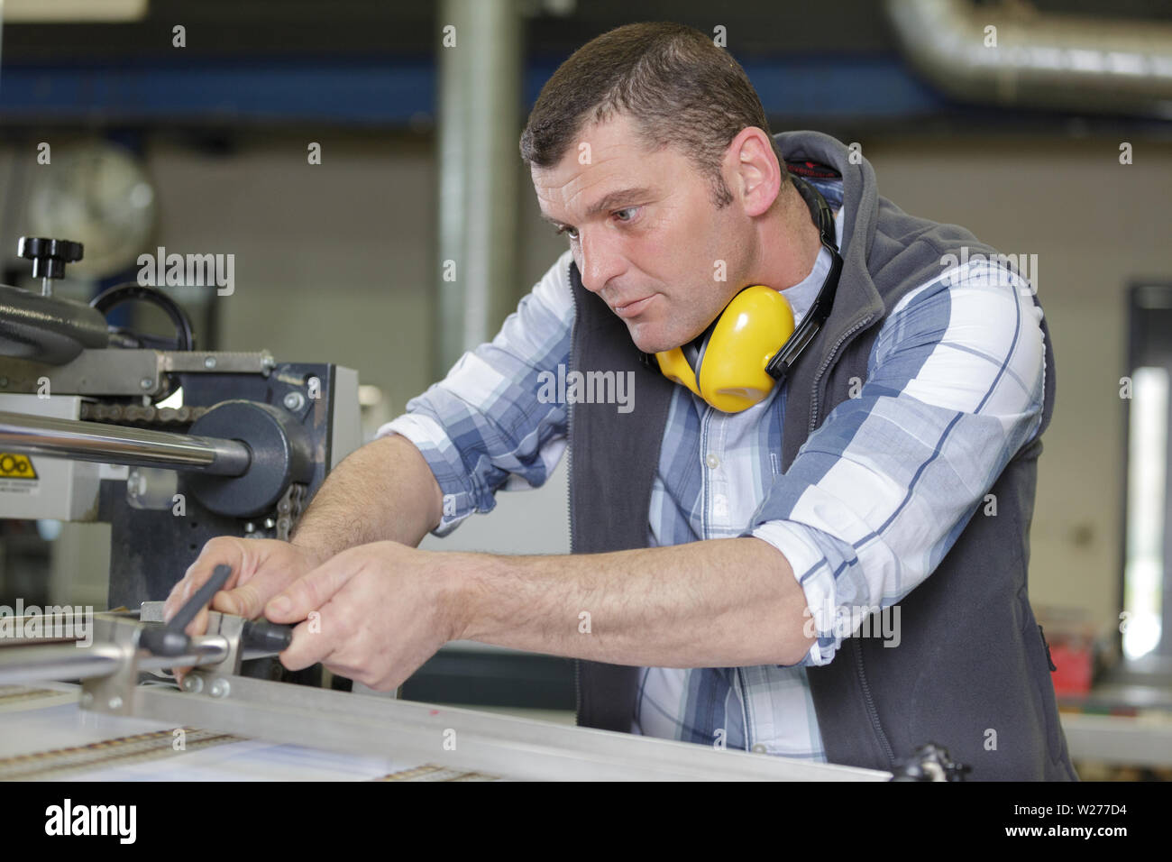 man wearing ear protectors cutting piece of wood Stock Photo - Alamy
