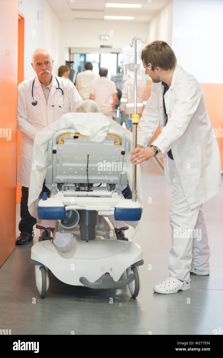 male hospital staff pushing bed along corridor Stock Photo - Alamy