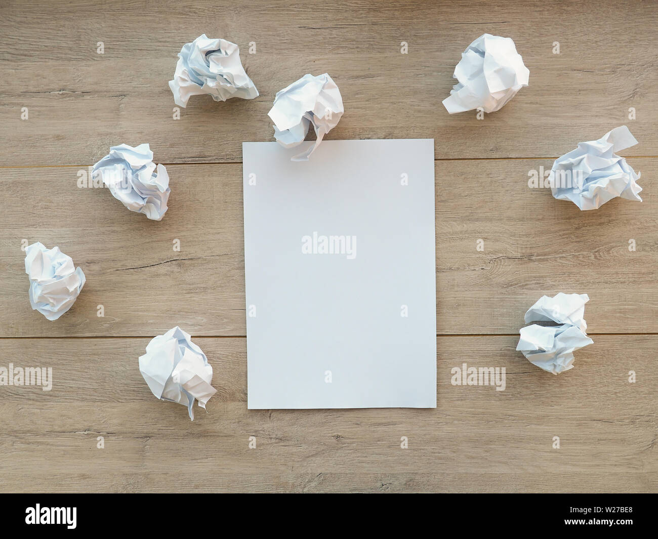 Writing concept - crumpled up paper wads with a sheet of white paper ...