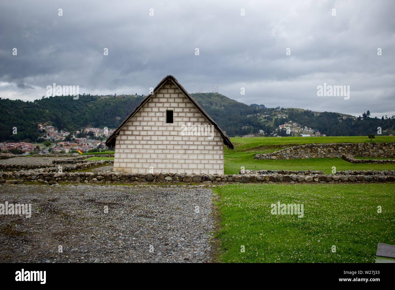 Hand-built stone house in a large beautiful green field with cloudy sky ...