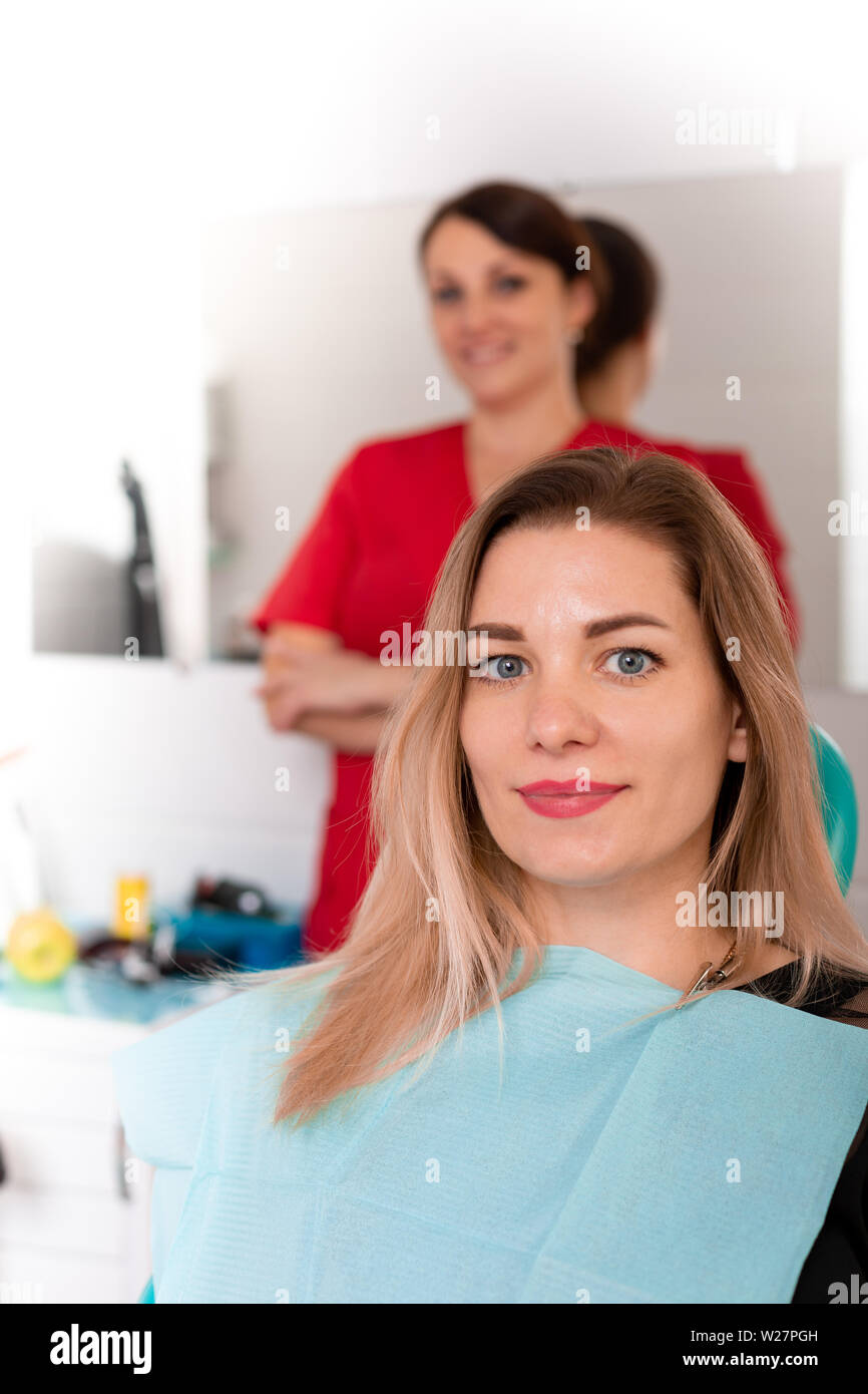 The dentist and her happy patient look at the camera and smile ...