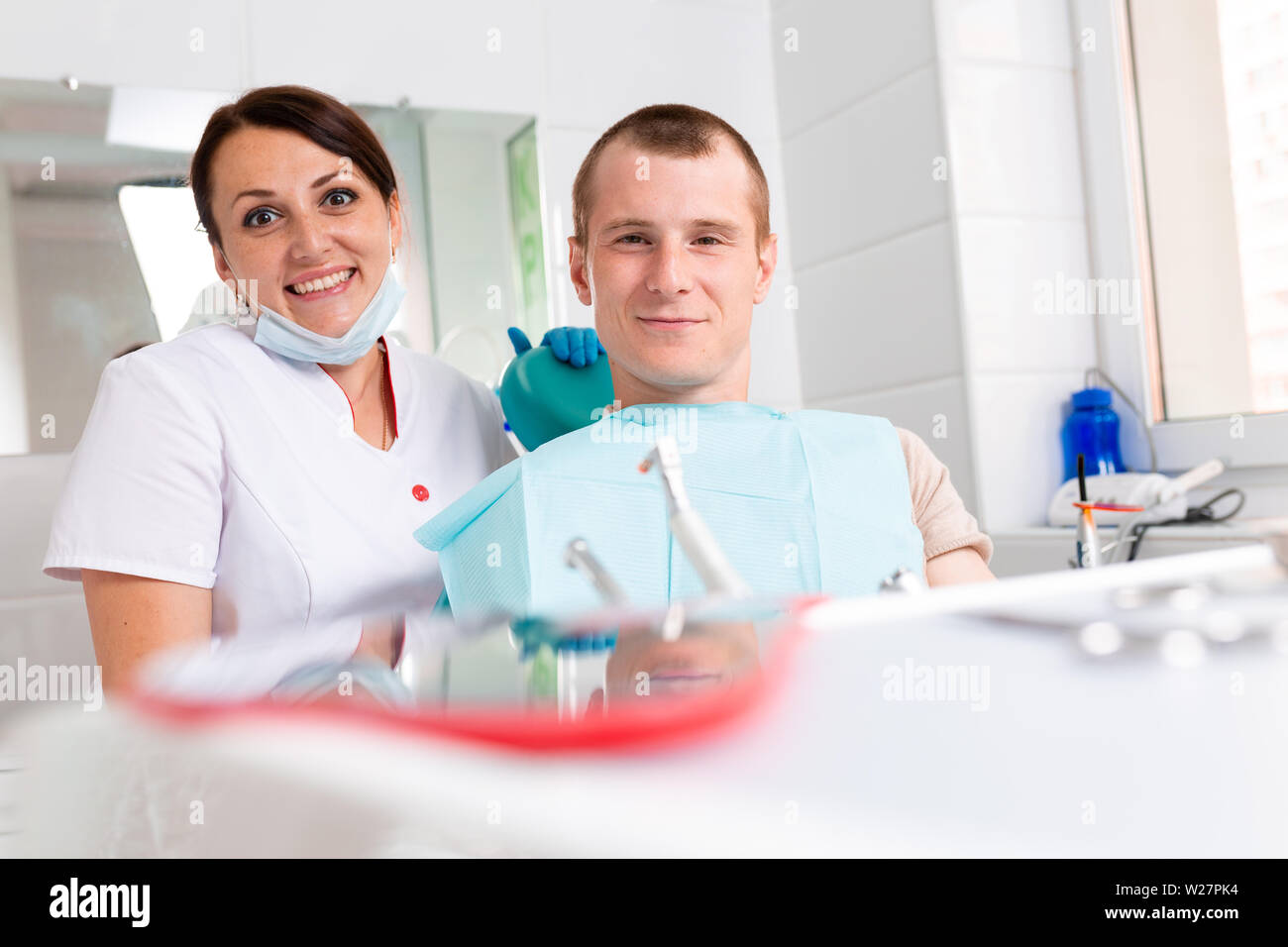 The dentist and her happy patient look at the camera and smile ...