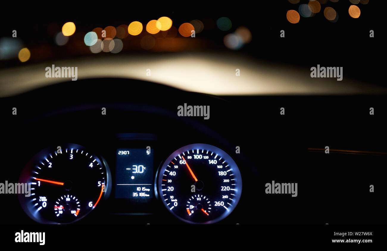 A blue and red car speedometer with blurred city lights on the ...