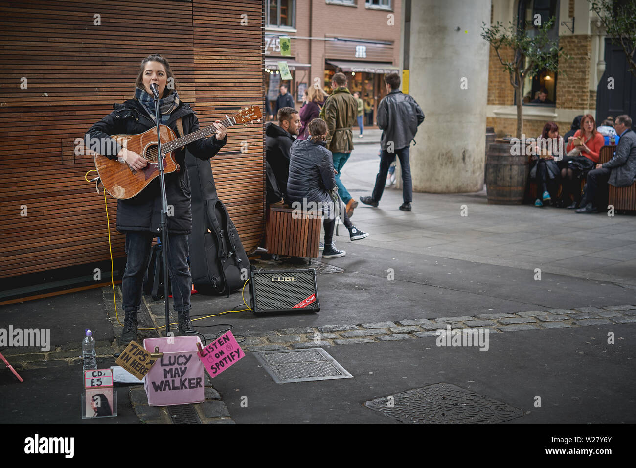 London, UK - April, 2019. A female young street musician performing in ...
