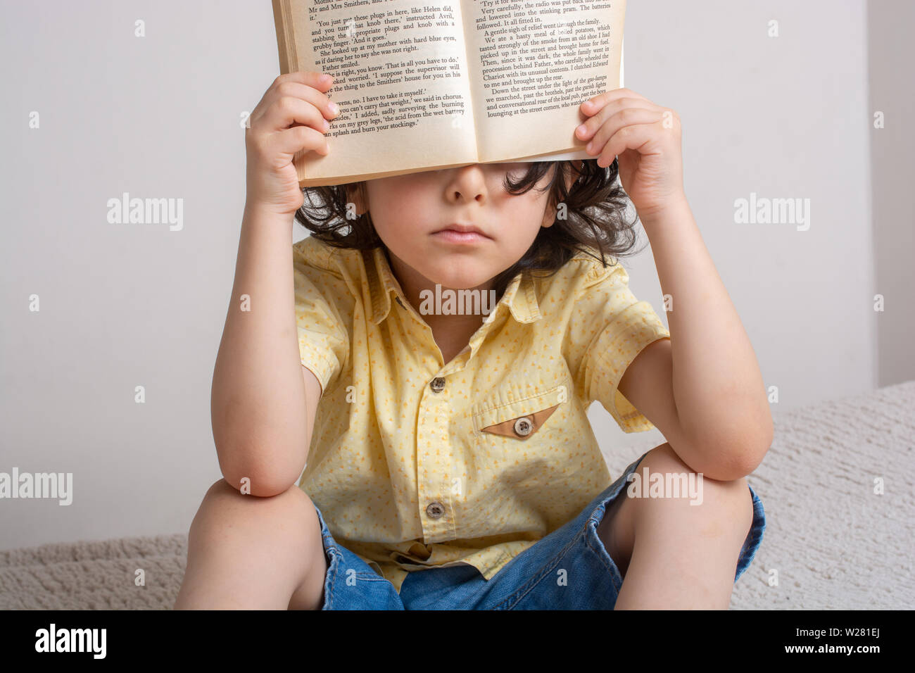 Boy covering eyes with book as education studying concept Stock Photo ...