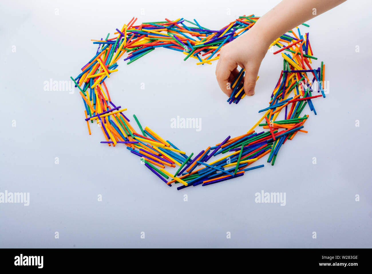Coloured sticks formed heart shape by hand on white background Stock ...
