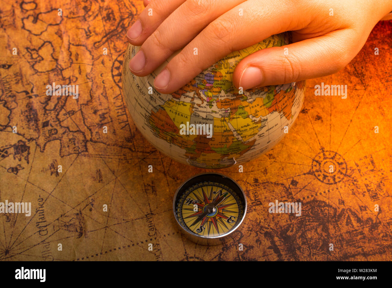 Compass on map beside a globe under hand Stock Photo - Alamy