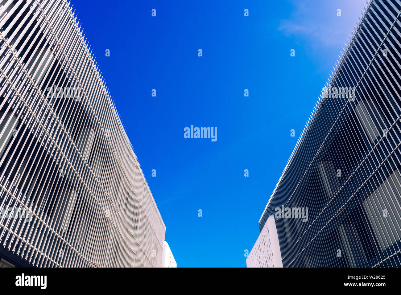 Two buildings converging on a blue sky background in the center Stock ...