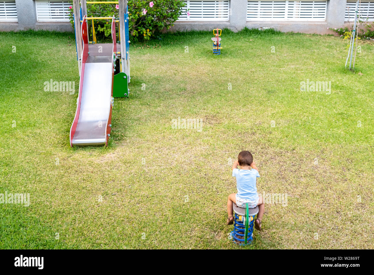 Boy playing alone in a playground, on his back, without his parents or ...