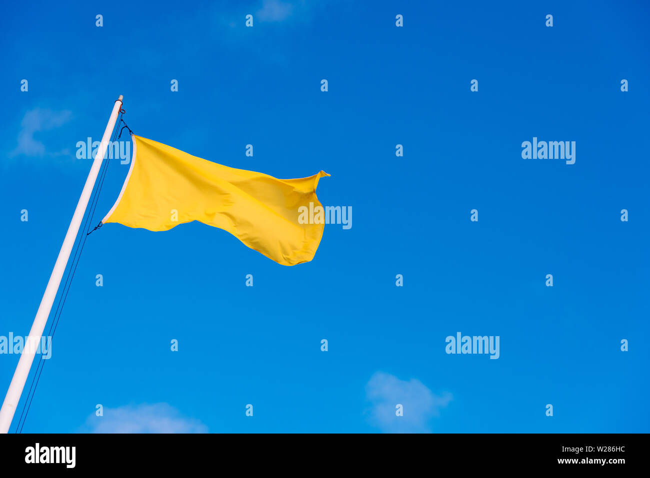Yellow warning flag on a beach against the blue sky background Stock ...