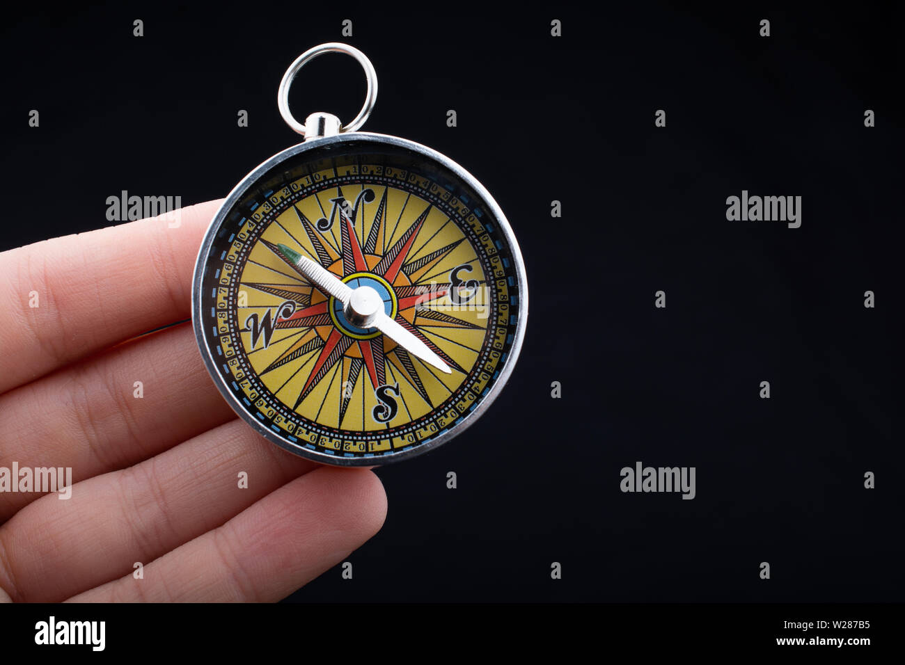 Hand is holding a magnetic compass on black background Stock Photo - Alamy