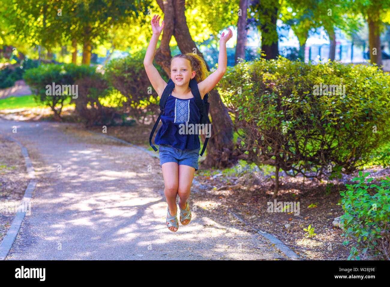 Little girl jumping on the sunny park in the day time .Happy smiling ...