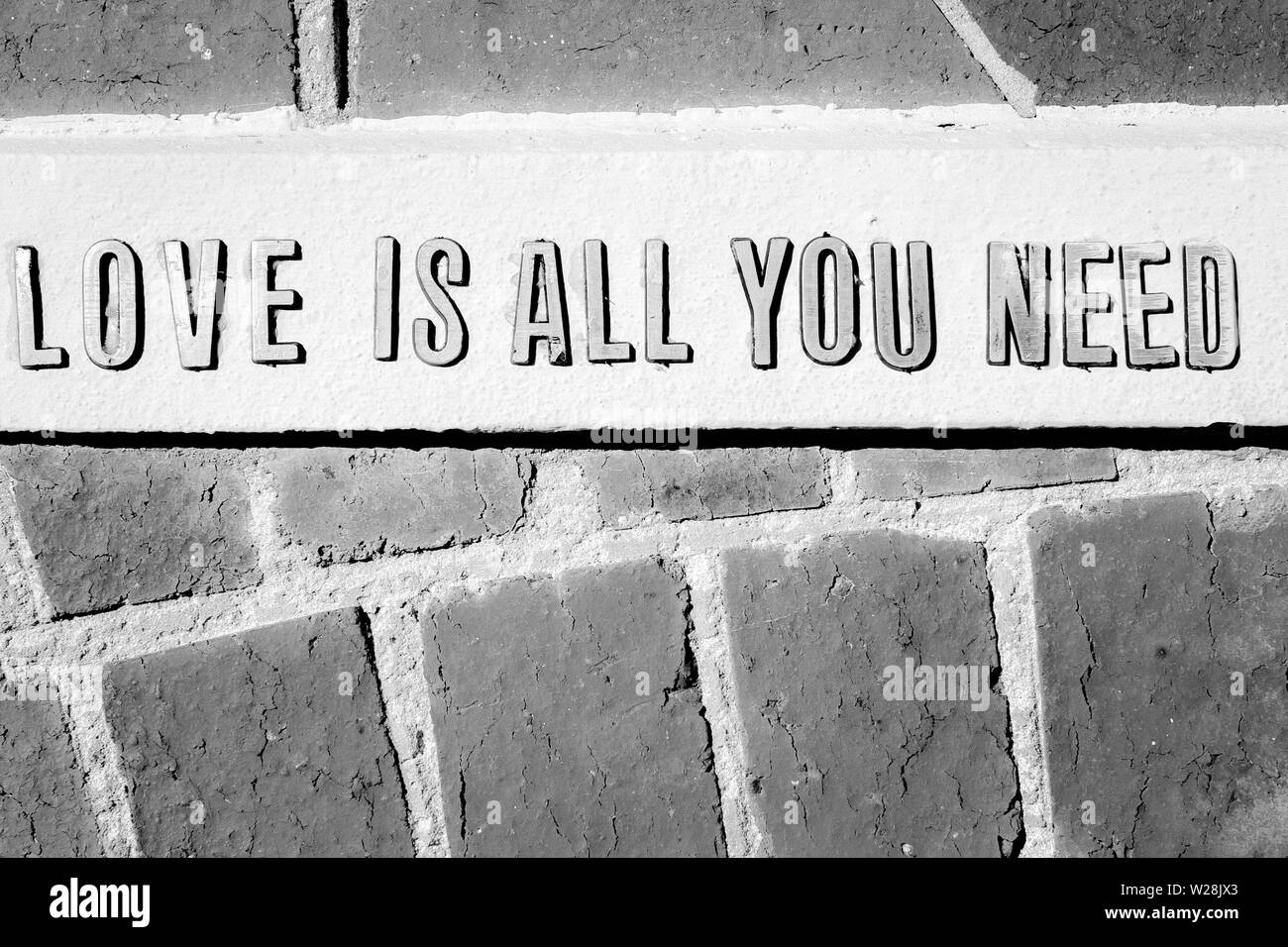 "Love is all you need" statement in raised lettering on a brick ...