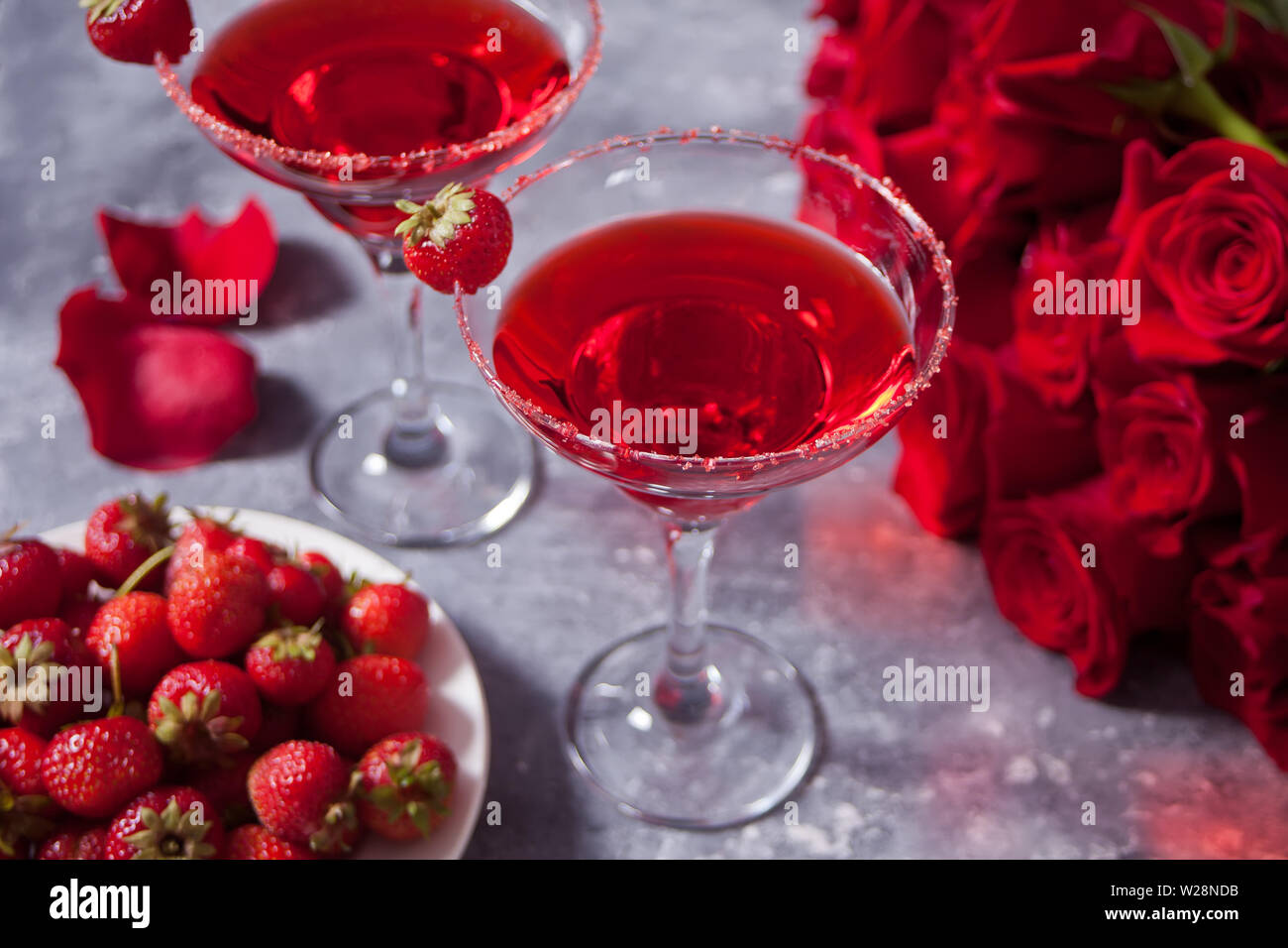 Two red fresh exotic alcoholic cocktail in clear glasses, red roses and ...
