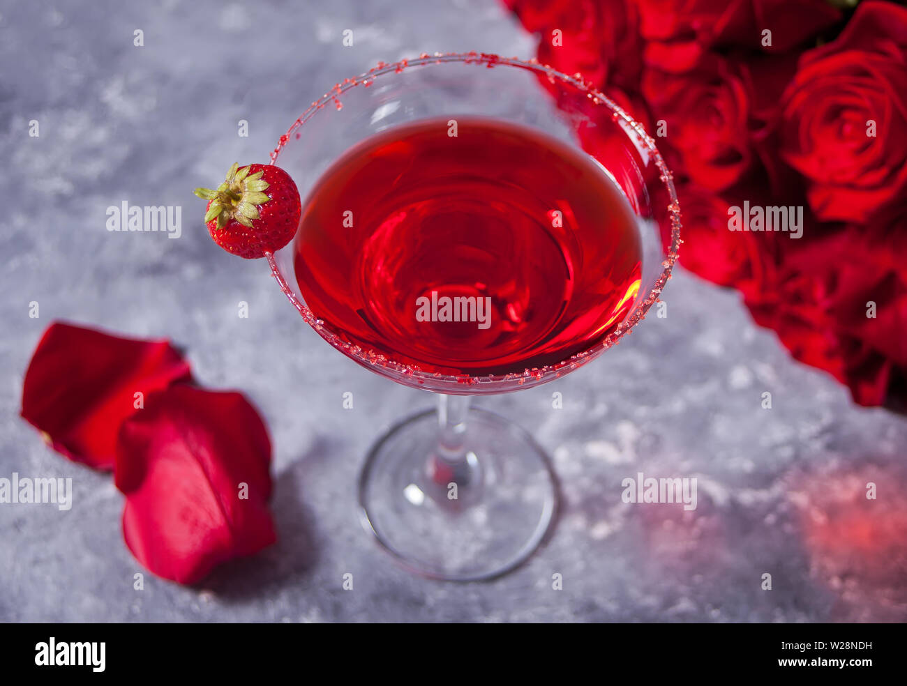 Red fresh exotic alcoholic cocktail in clear glass and red roses on the ...